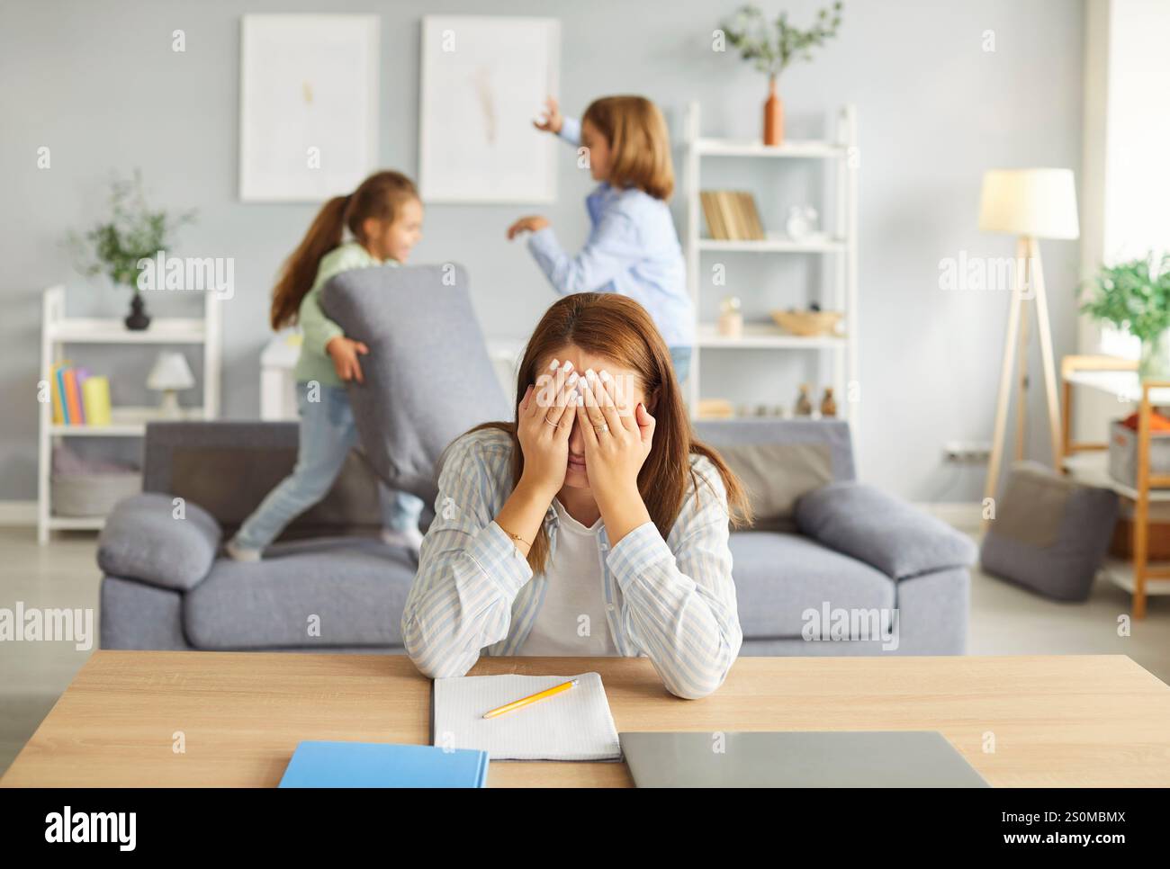 Tired Mother Working At Home With Noisy Kids Playing Around Stock Photo - Alamy