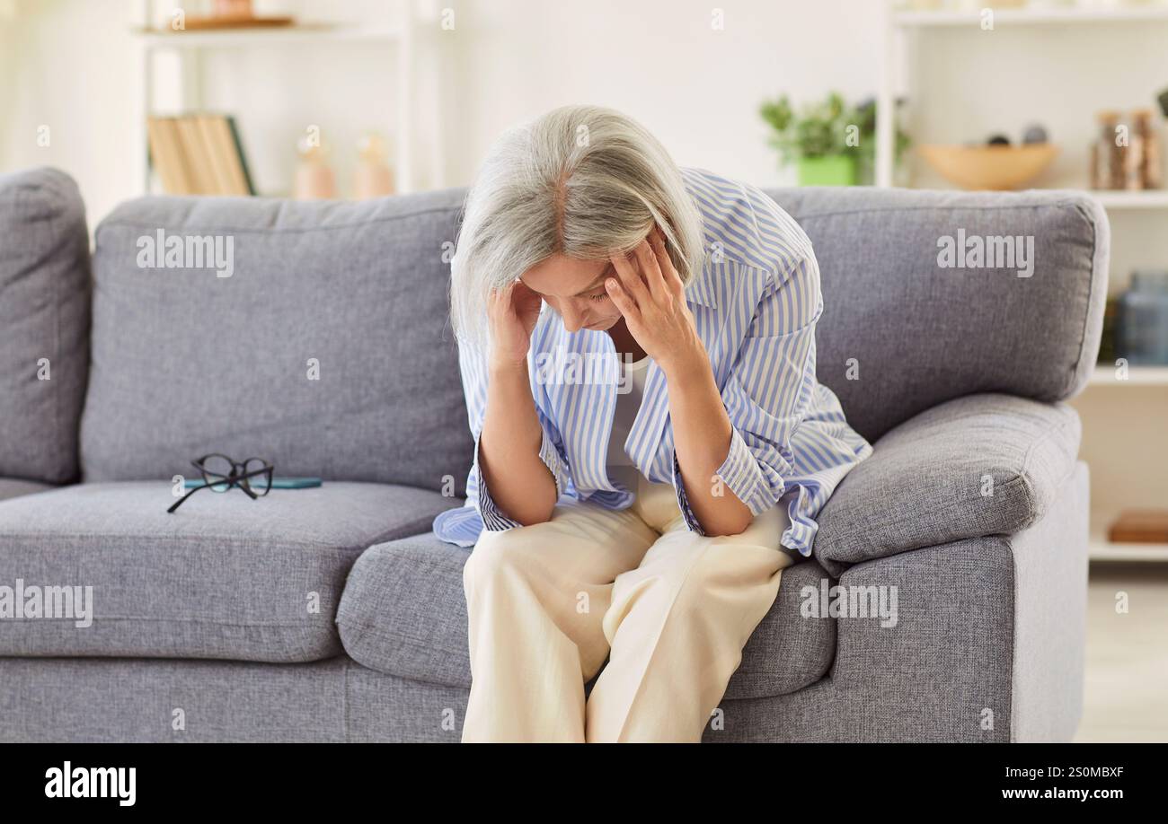 Senior sad, old aged lady looking down sitting alone at home, feels ...