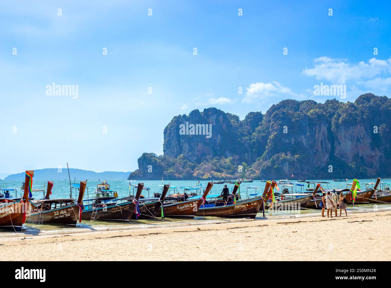 Thai longtail boats stand in a sea bay against the backdrop of mountain ...