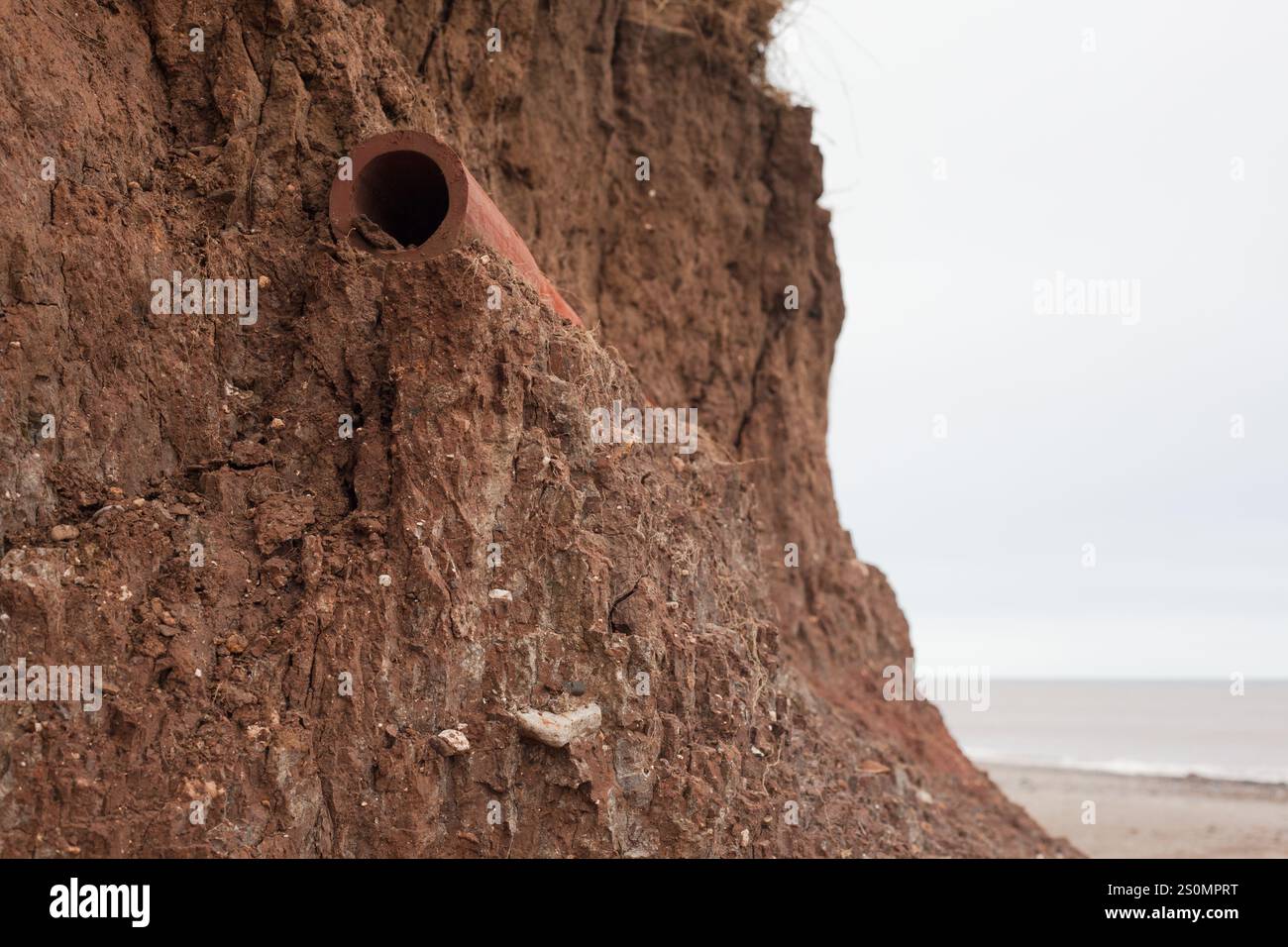 Broken orange clay drainage pipe exposed by coastal erosion at Spurn ...