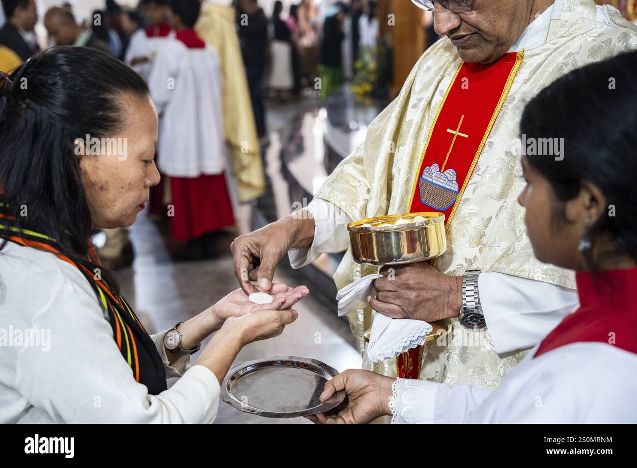 Devotees take holy communion from a priest during a Christmas day ...