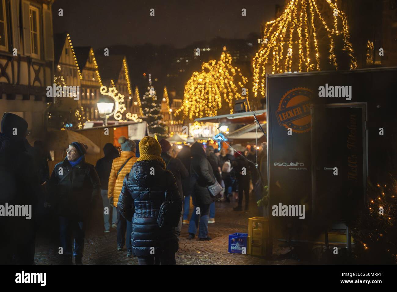 Festive Christmas market at night with many visitors and illuminated ...