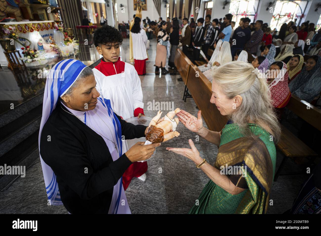 A priest holds an idol of baby Jesus Christ as devotees kiss the idol ...