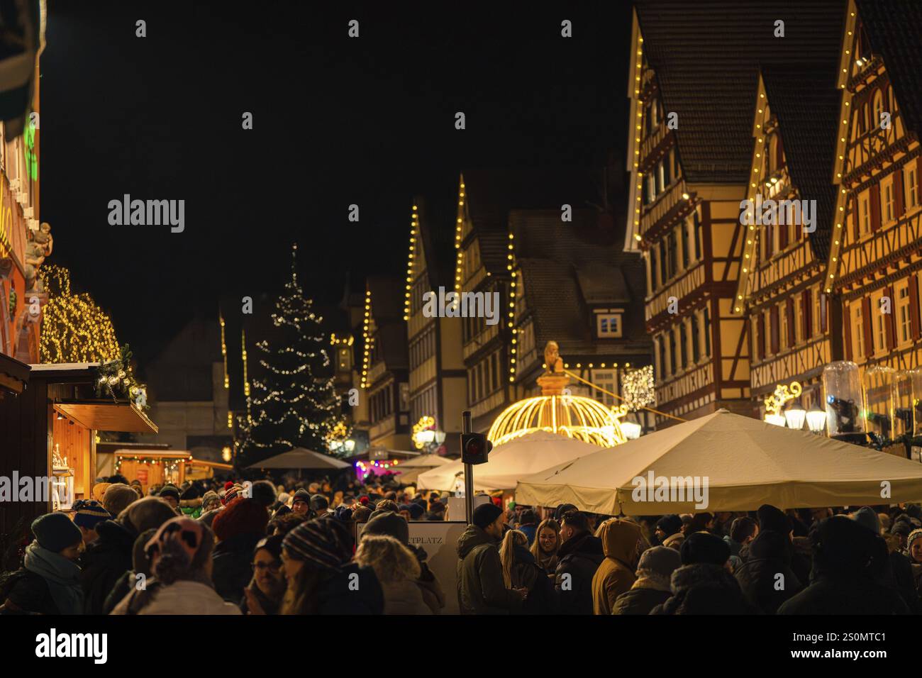 A night market full of people with half-timbered houses and festive ...