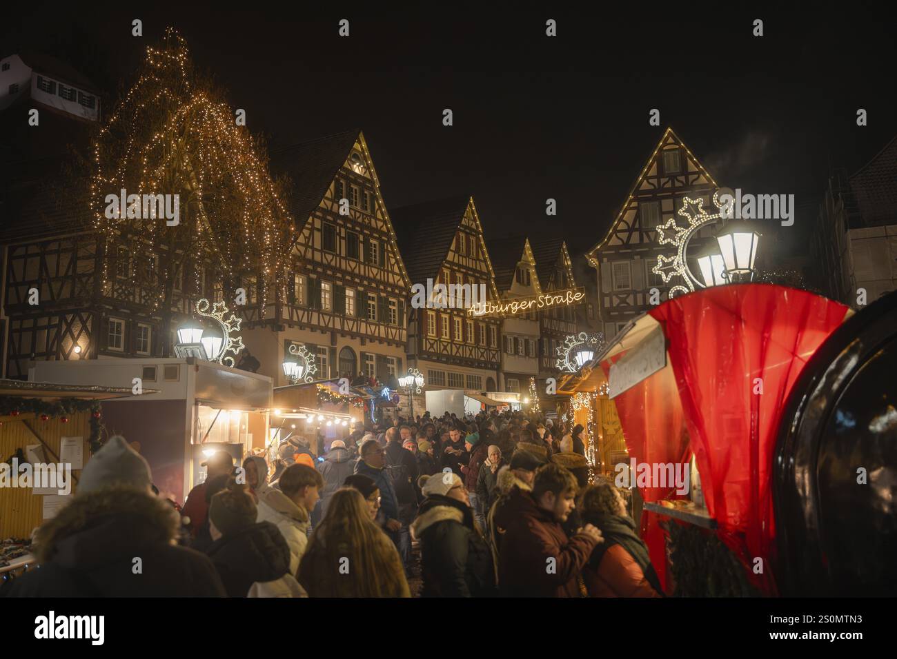 Dense crowds at a Christmas market in a festively illuminated old town ...