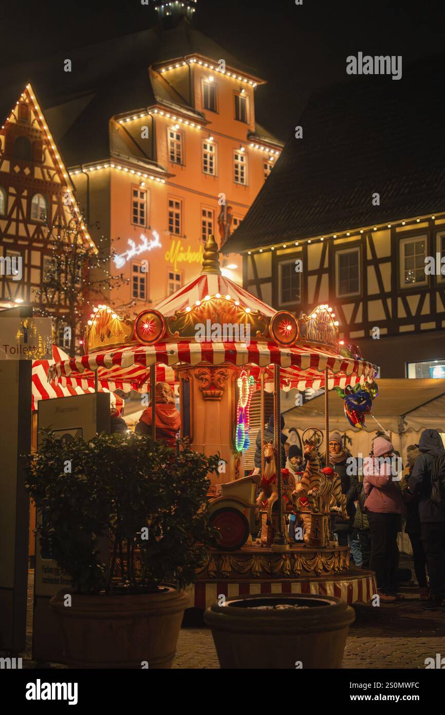 Festively illuminated carousel at a historic Christmas market at night ...