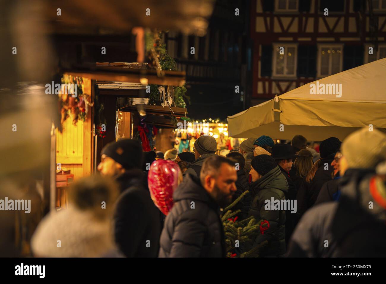 Numerous people visit an illuminated night market with decorated stalls ...
