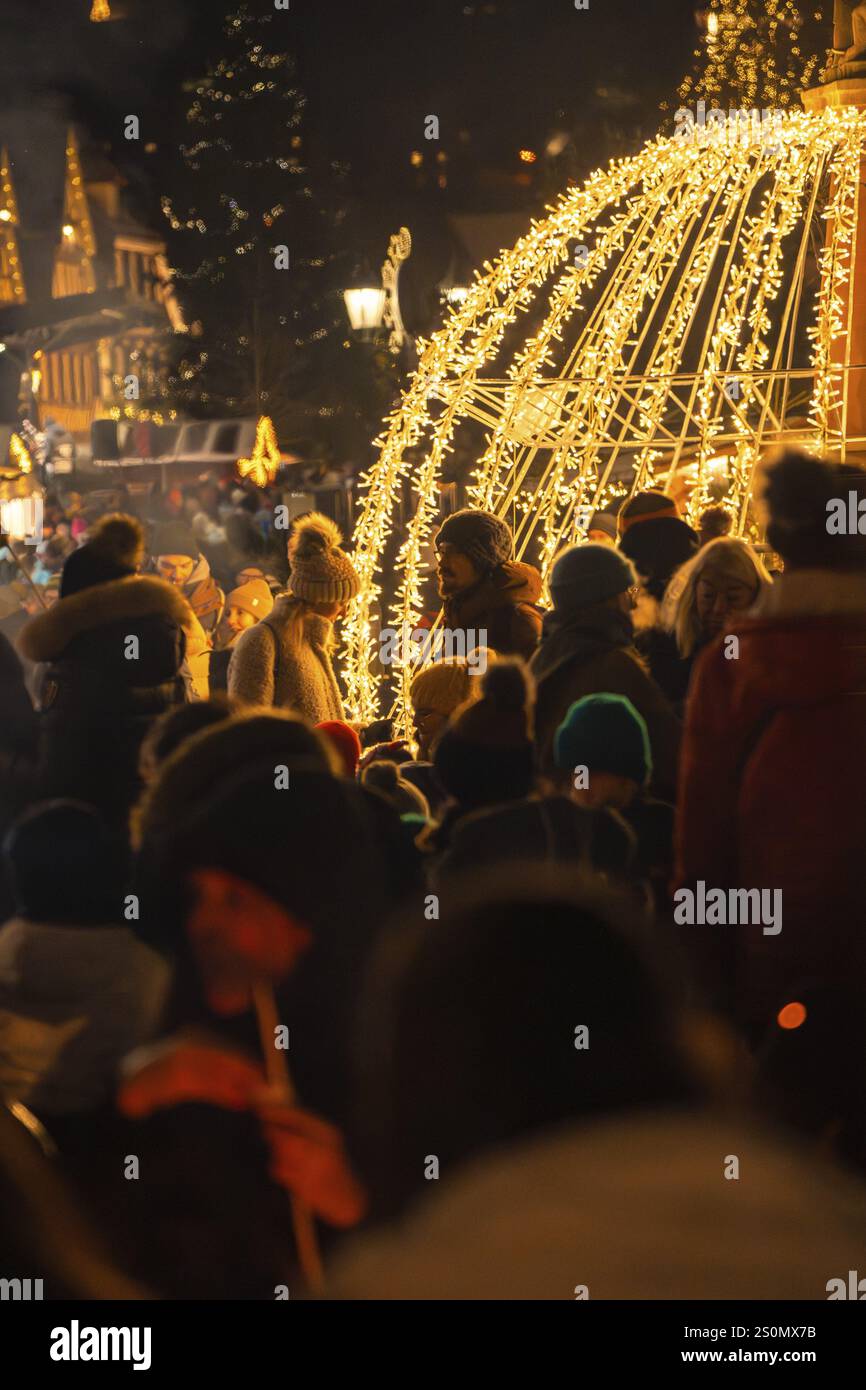 People at a Christmas market under an illuminated arch of lights at ...