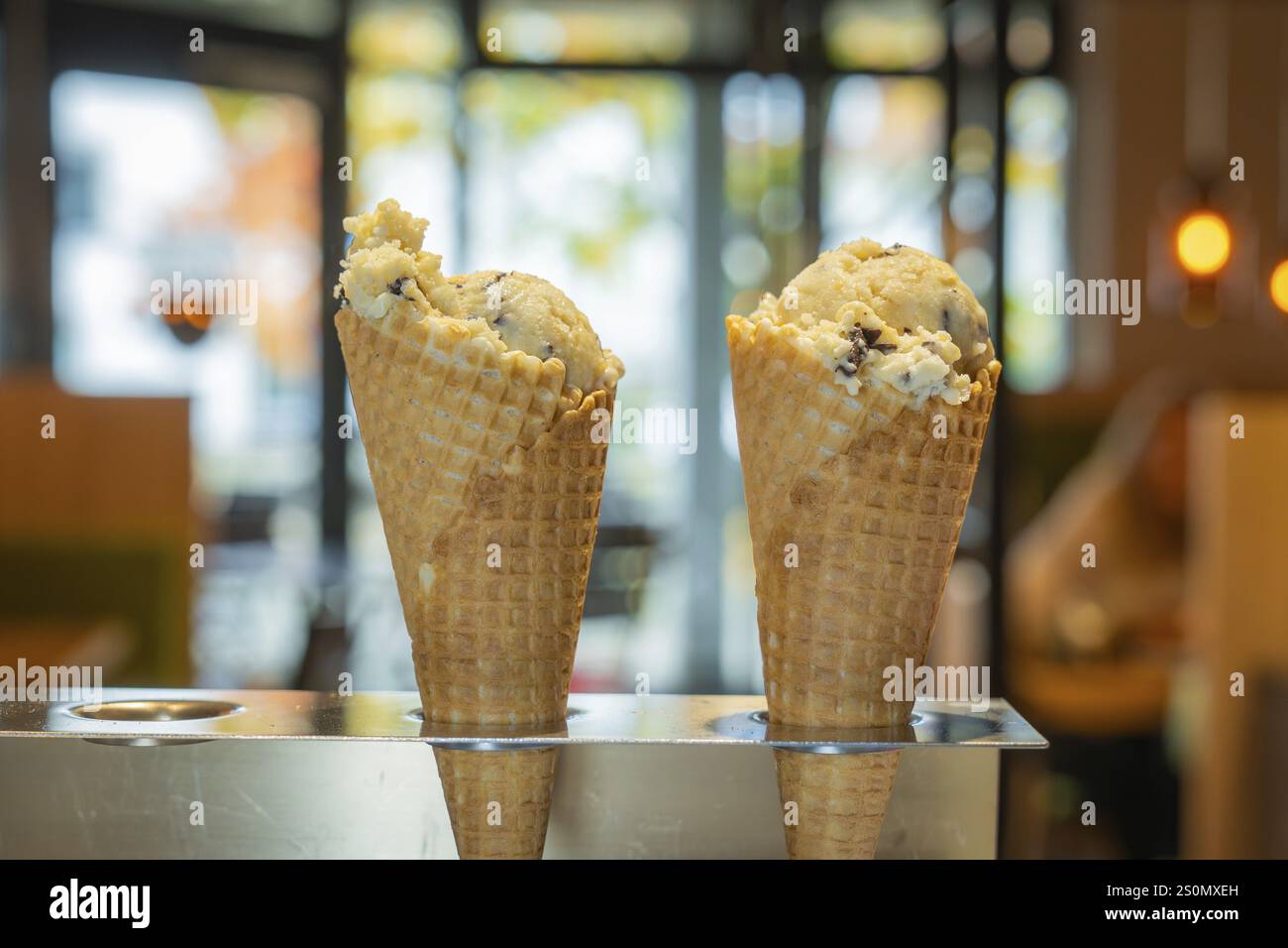 Two ice cream cones in the foreground in front of a warm cafe ambience ...