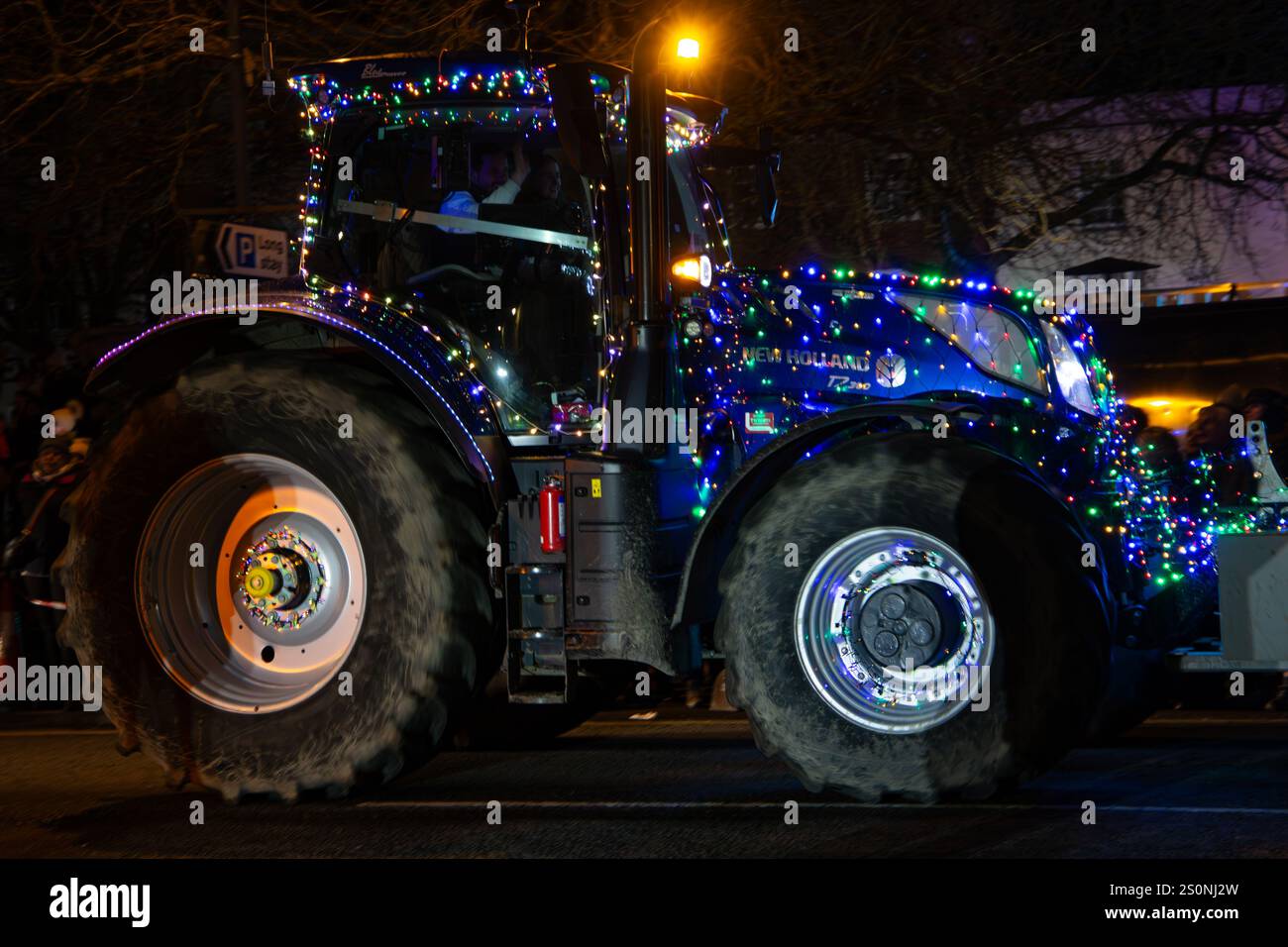 A tractor decorated with colorful Christmas lights drives through a ...