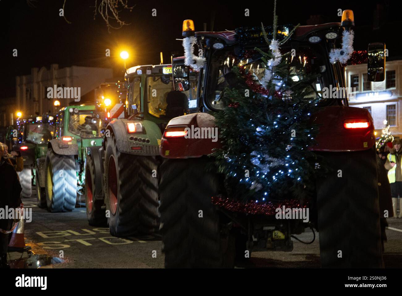 A tractor decorated with colorful Christmas lights drives through a ...