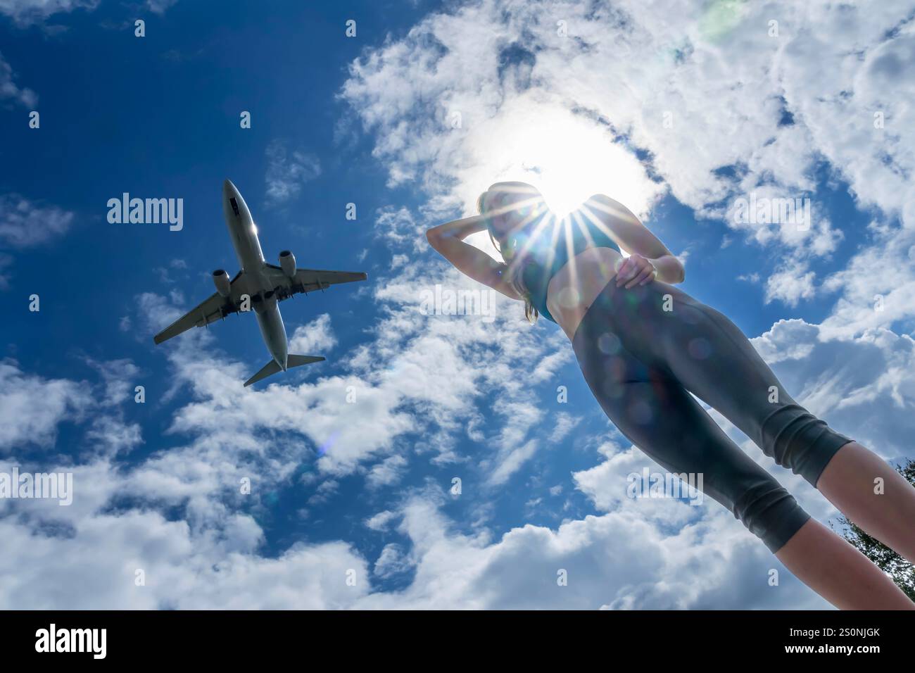 A vibrant young woman stretches on a park trail, sunlight dancing on ...
