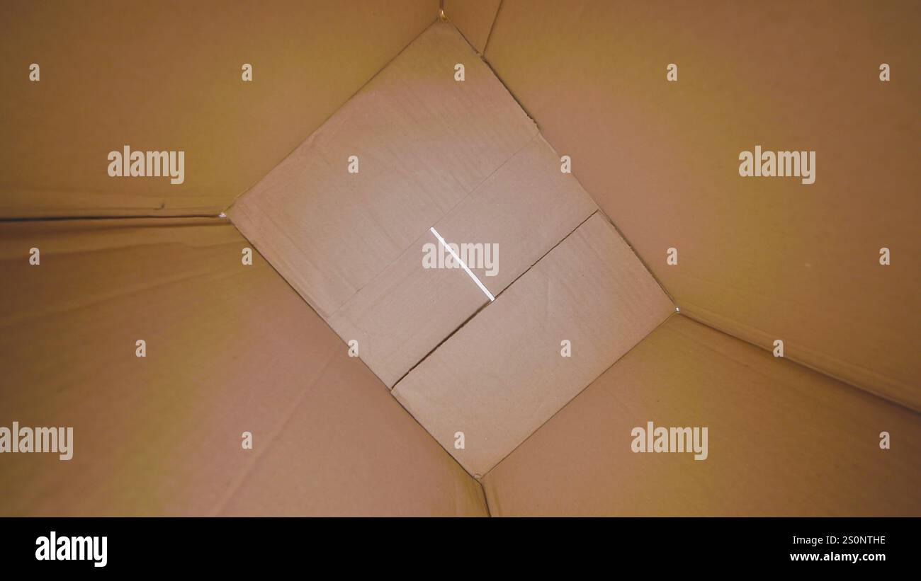 Light is entering a cardboard box from a small opening, creating a ...