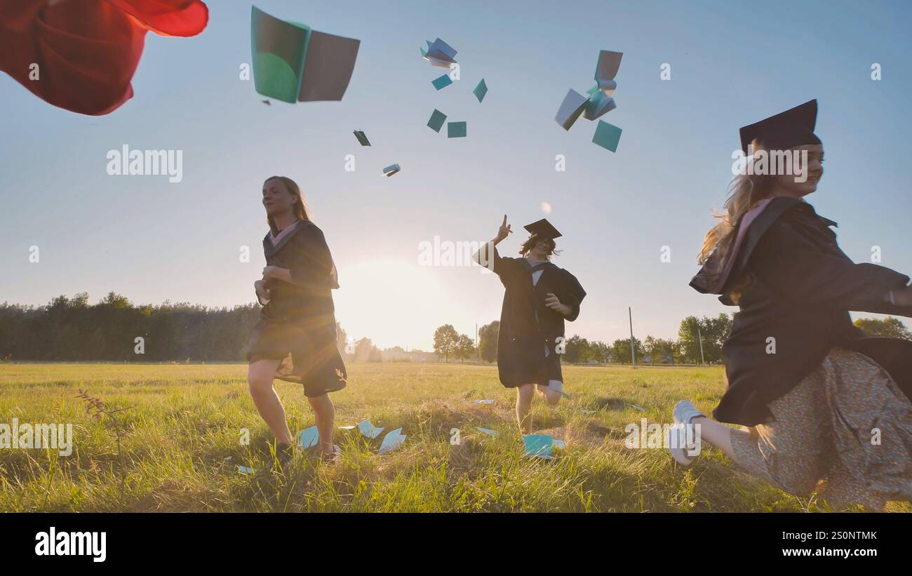 High school graduates joyfully tossing their caps and books in the air ...
