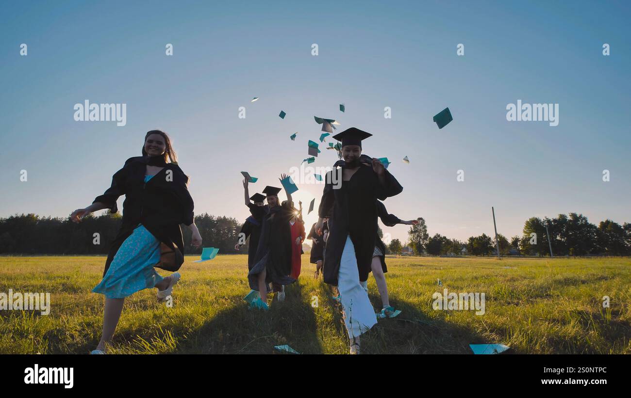 Cheerful graduates celebrating their graduation by tossing diplomas and ...
