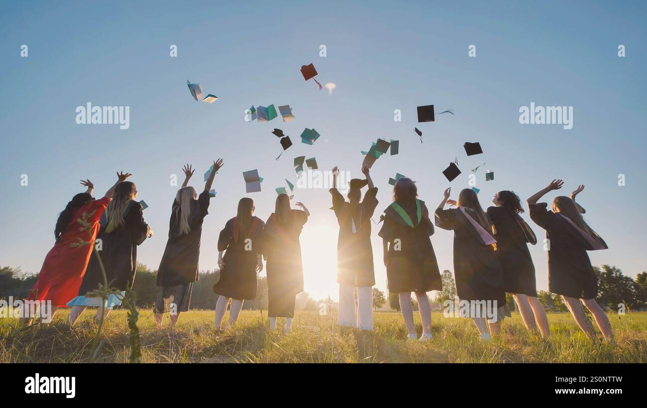 Graduates tossing caps and books in the air at sunset to celebrate ...