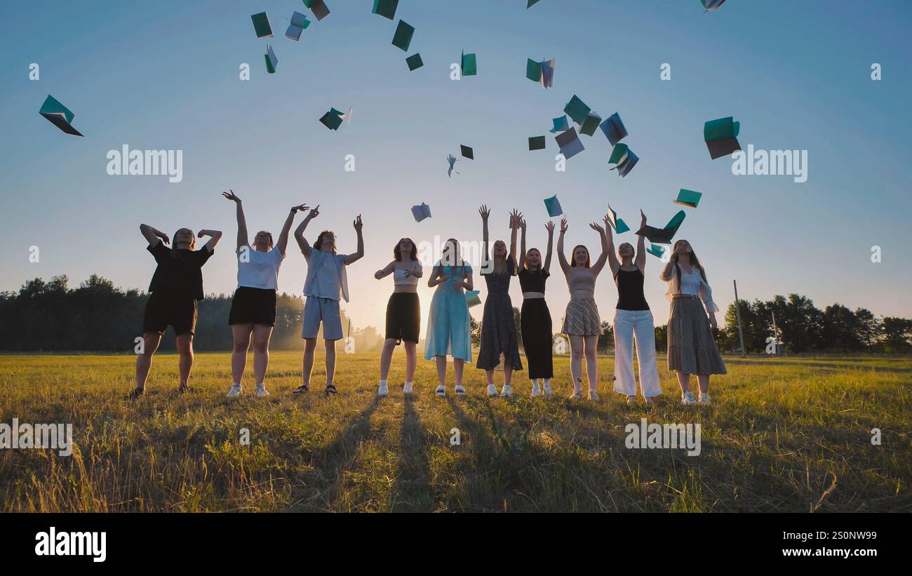 Group of joyful high school students throwing books up in the air ...