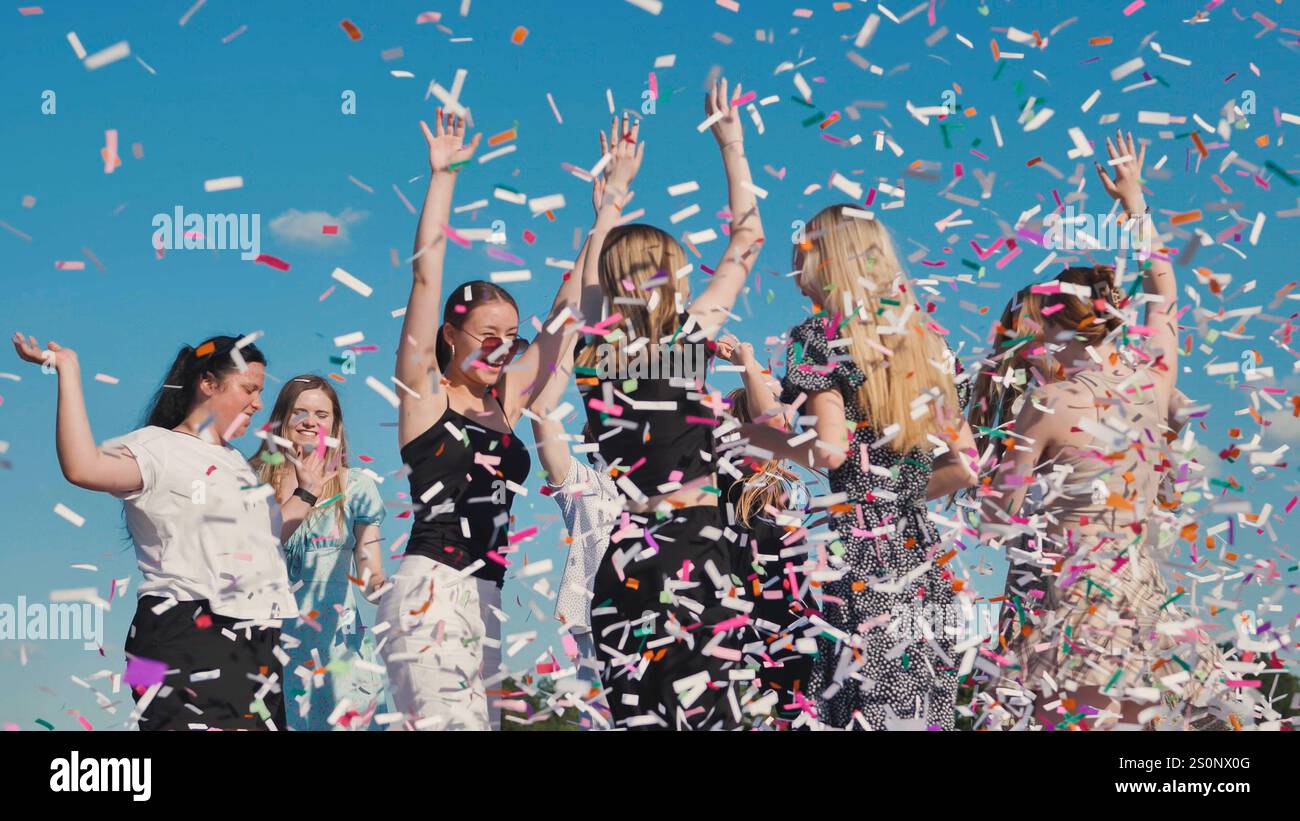 Teenage girls celebrate graduation by tossing colorful confetti into ...