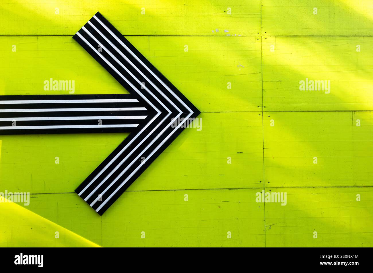 A bold black and white striped arrow affixed to a vibrant lime green ...