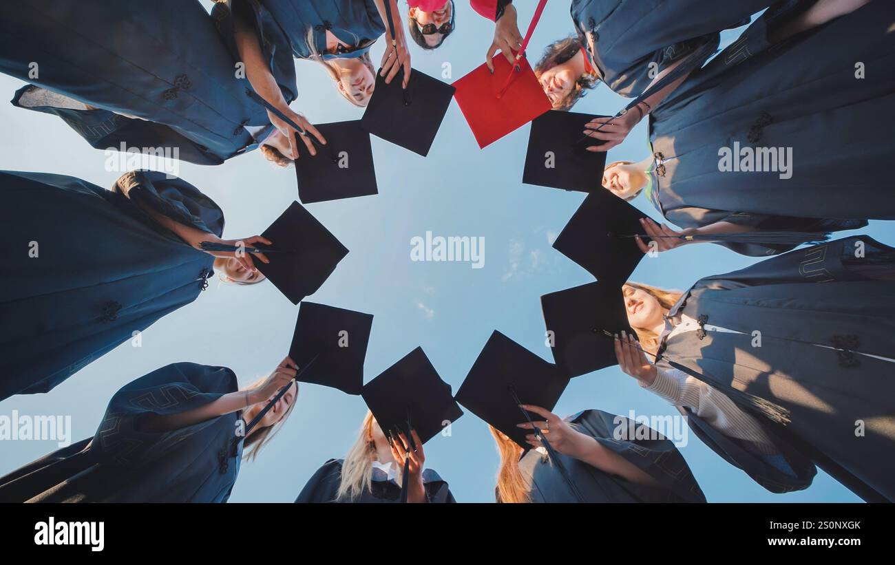 Group of students wearing graduation gowns making circle with their ...