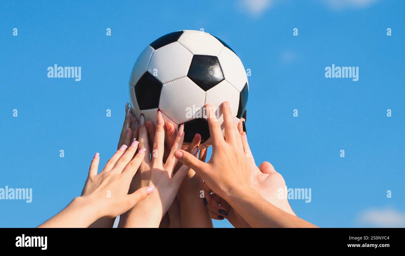 Friends demonstrating teamwork and unity by raising a soccer ball above ...