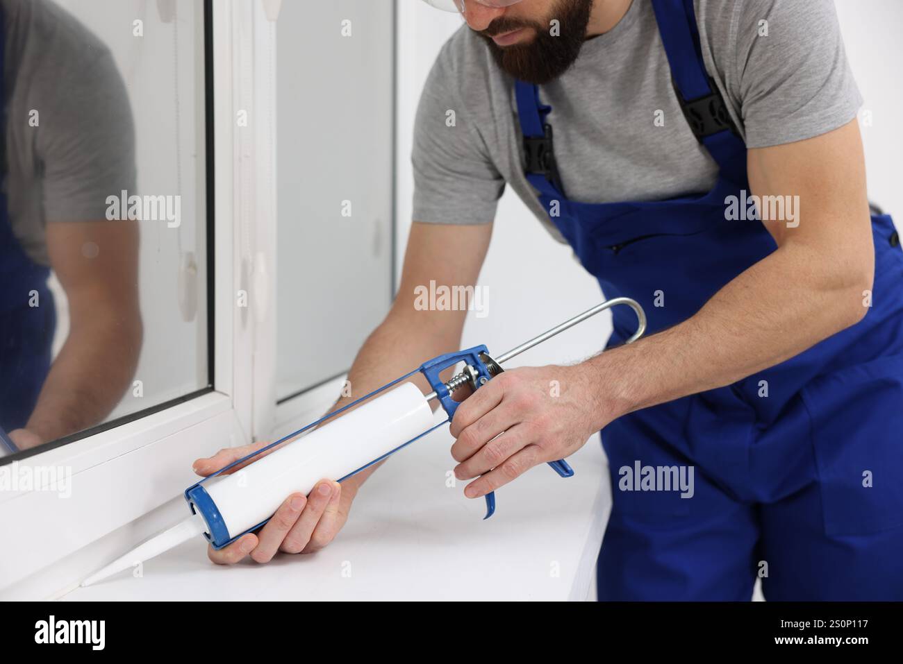 Worker with caulking gun sealing window indoors, closeup Stock Photo ...