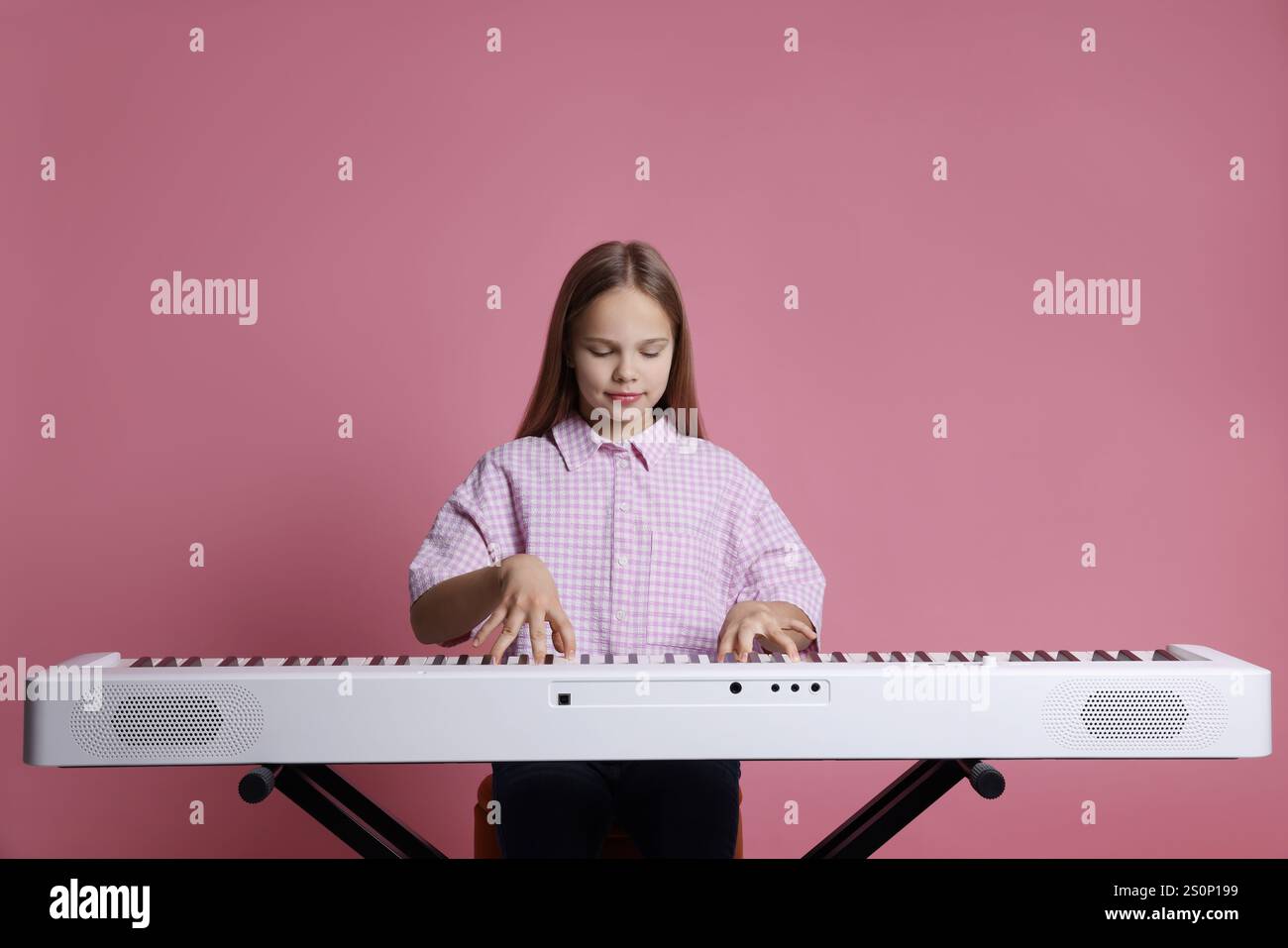 Cute girl playing synthesizer on pink background Stock Photo - Alamy