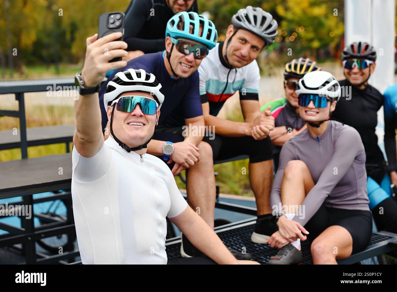 Group of athletic people with helmets and bicycles taking selfie ...