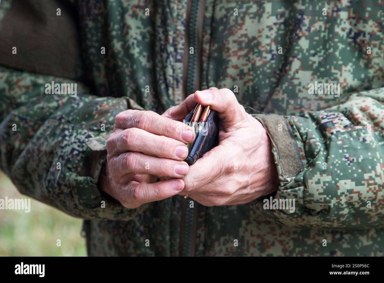 Soldier hands load rifle machine gun bullets into cartridge clip. High ...