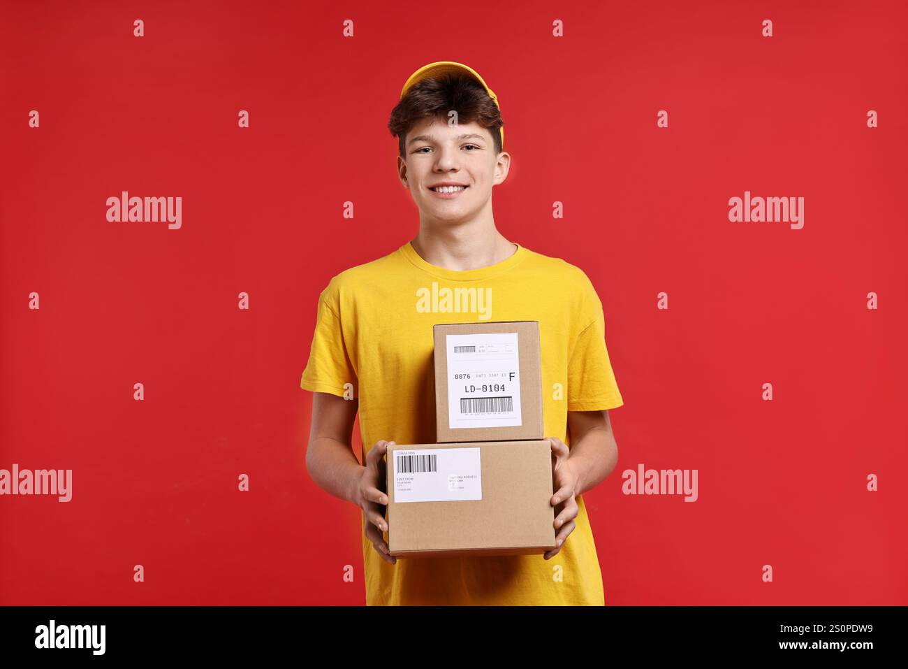 Teenage boy with parcels working as courier on red background Stock ...