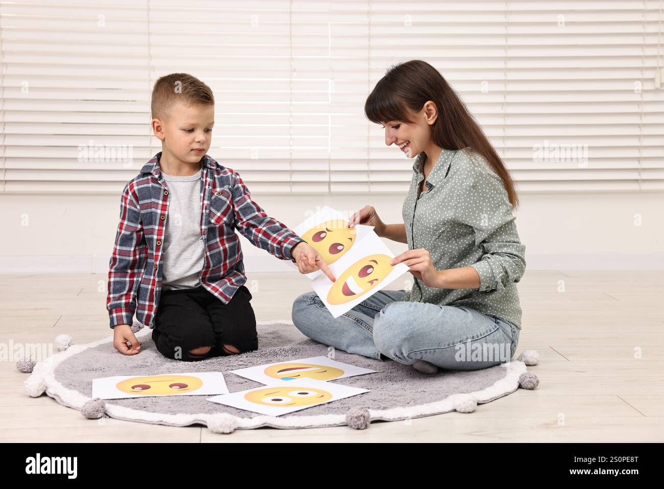 Autism therapy. Little boy choosing emoticon with smiling psychologist ...