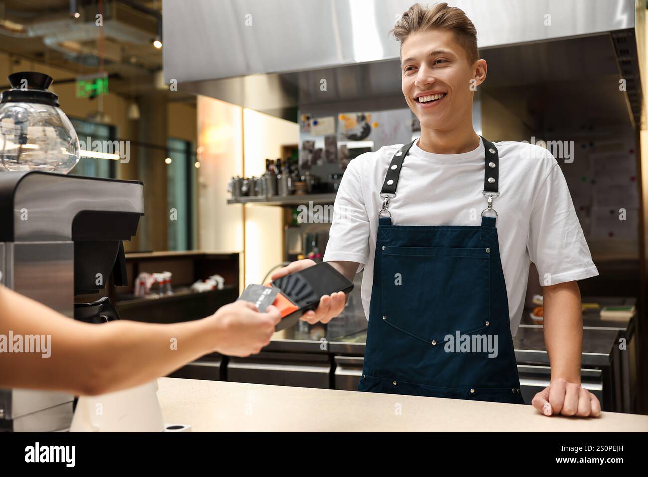 Cafe worker taking payment from client via terminal indoors Stock Photo ...