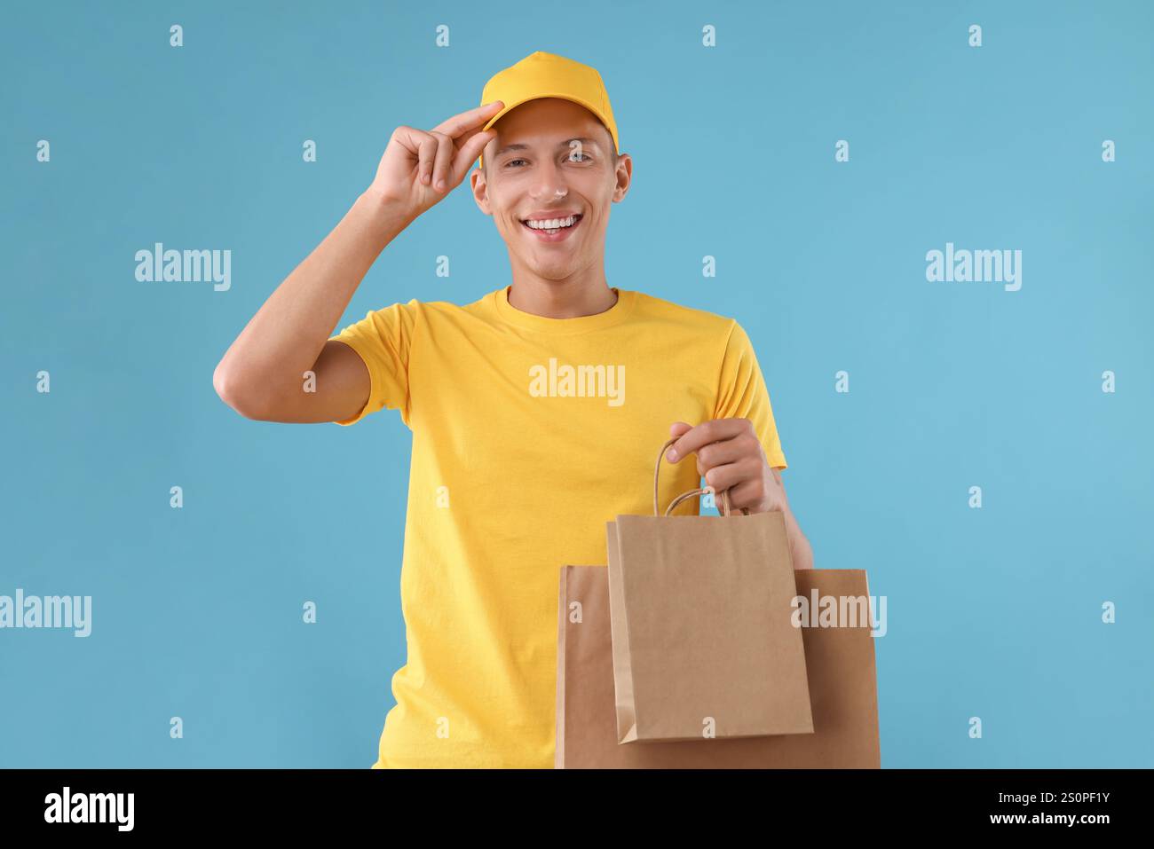 Fast-food worker with paper bags on light blue background Stock Photo ...