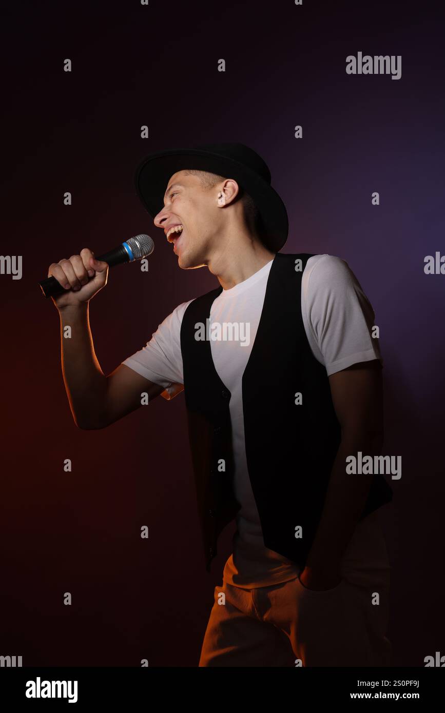 Talented young man singing on dark background with color light Stock ...