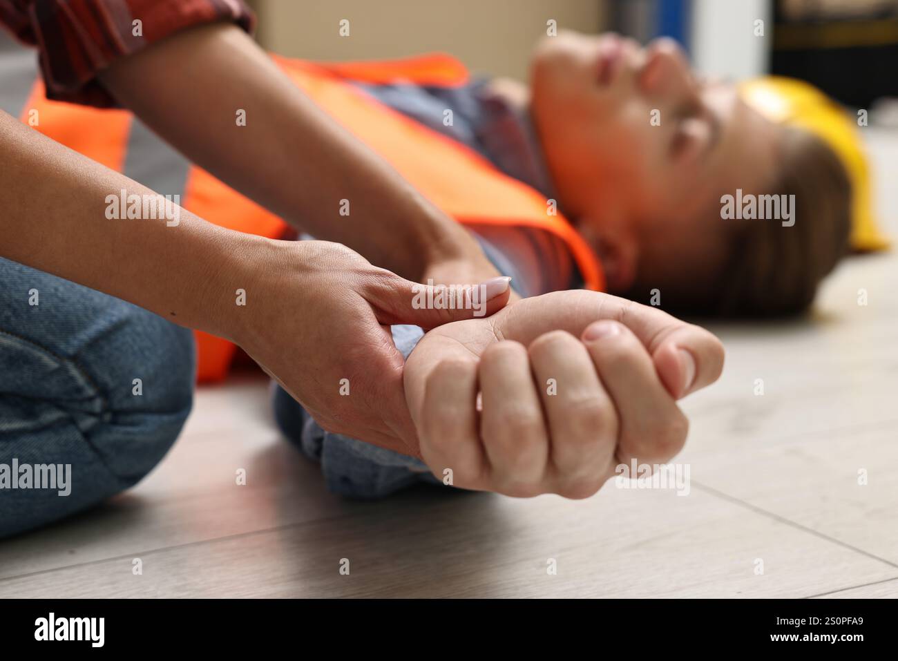 First aid. Woman checking pulse of her unconscious colleague indoors ...