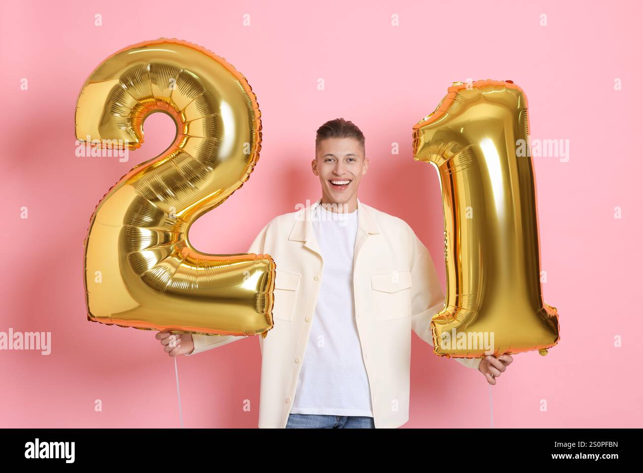 Coming of age party - 21st birthday. Happy young man with number shaped ...