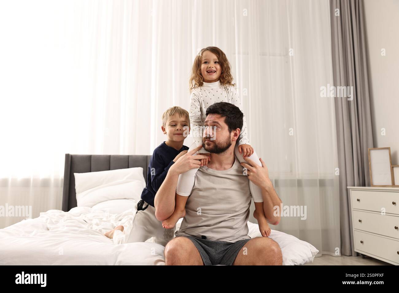 Overwhelmed father and his playful children on bed at home Stock Photo ...