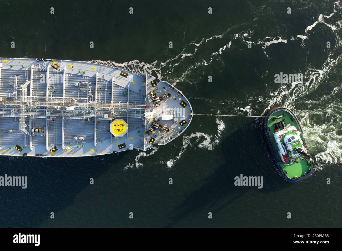 Aerial view of a large oil tanker and assisting tug boats in the port ...