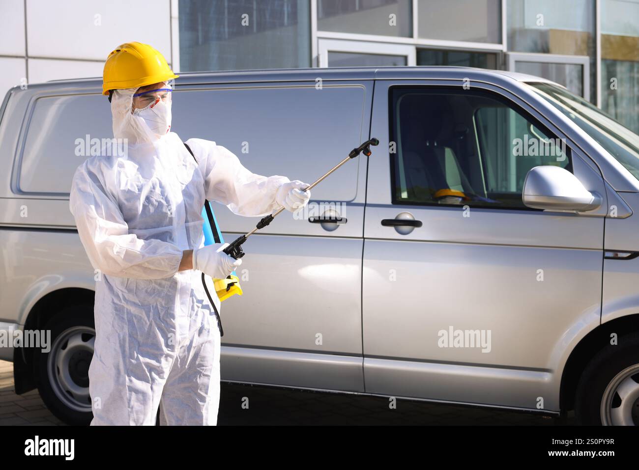 Pest control worker with spray tank near gray minibus outdoors Stock ...