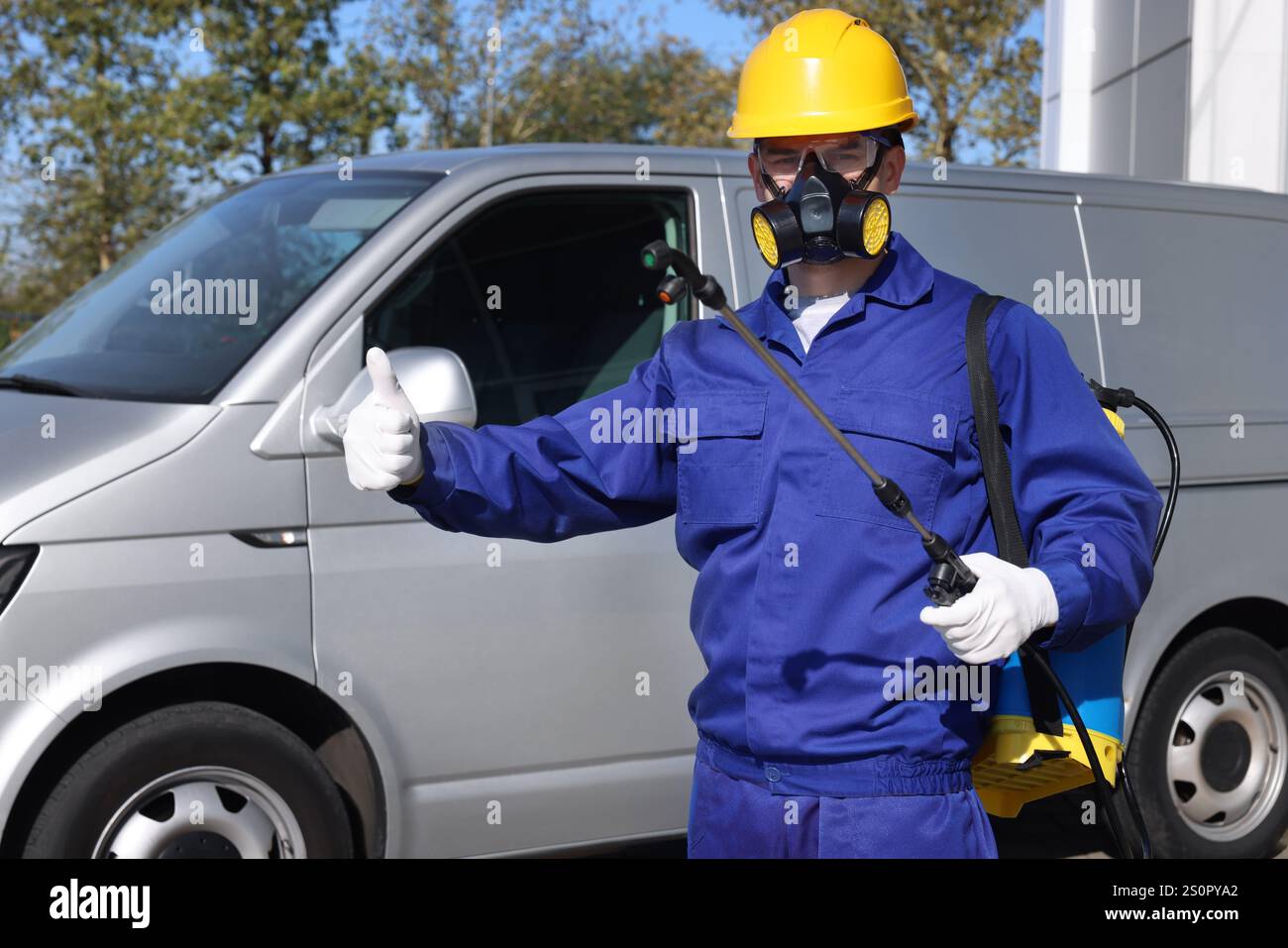 Pest control worker with spray tank showing thumbs up outdoors Stock ...