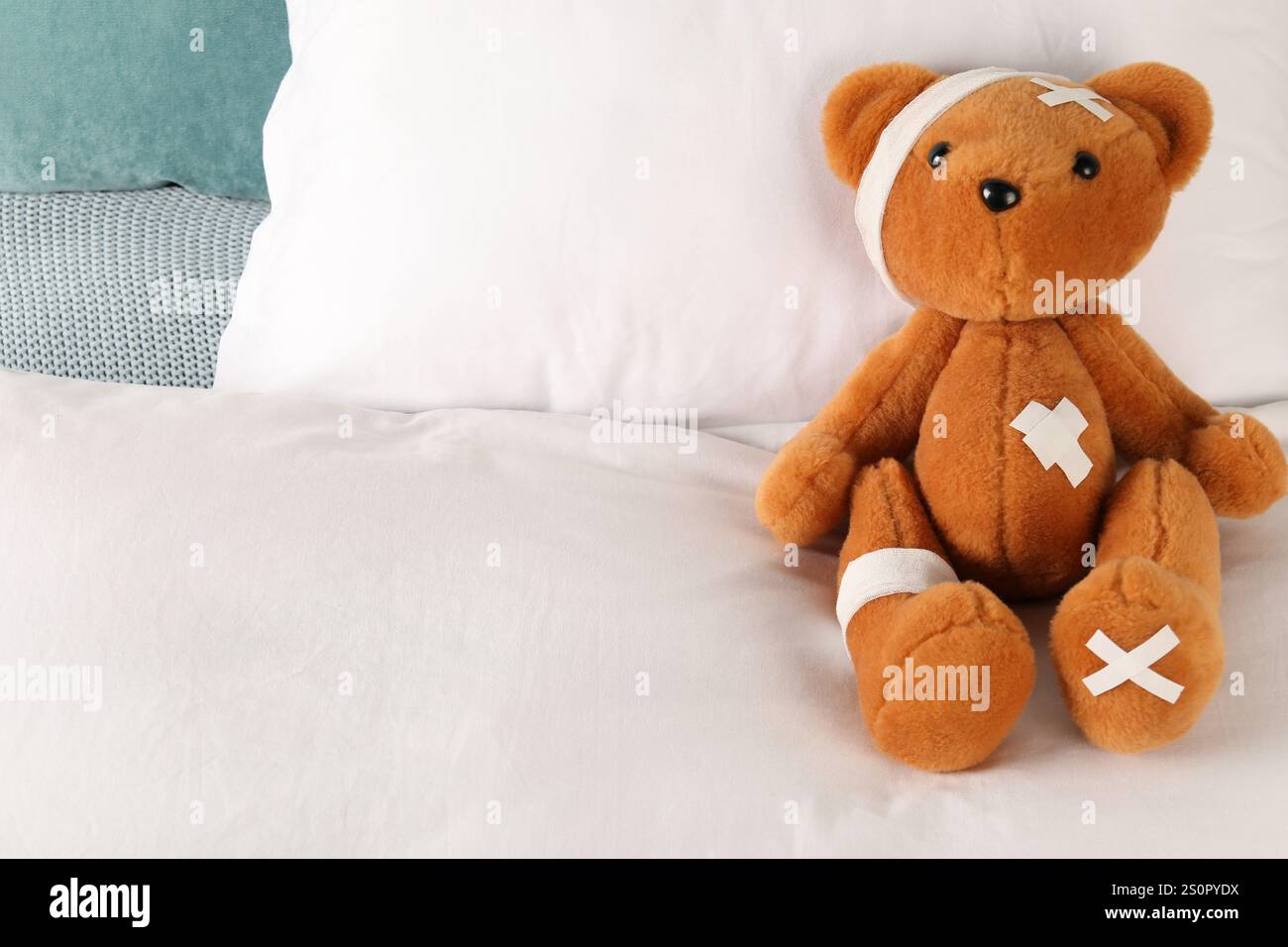 Cute teddy bear with bandages and adhesive medical plasters on bed ...