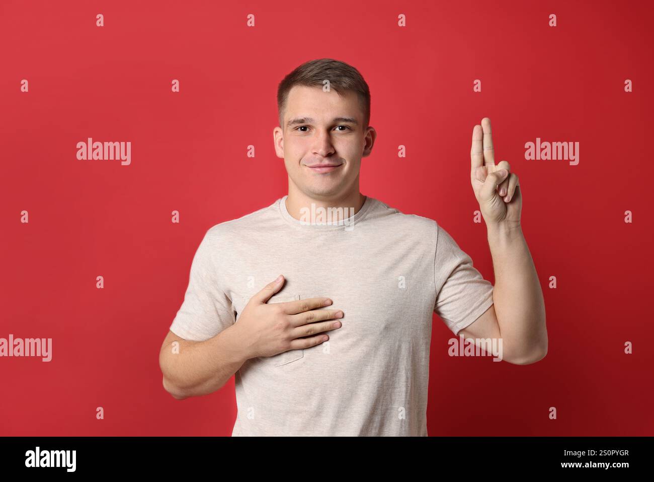 Man showing oath gesture on red background. Making promise Stock Photo ...
