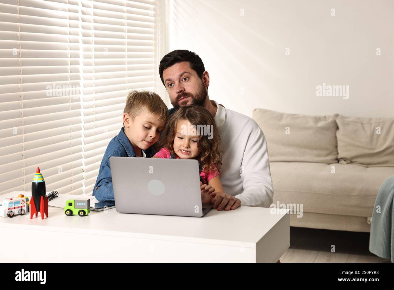 Naughty children disturbing their overwhelmed father at table with ...