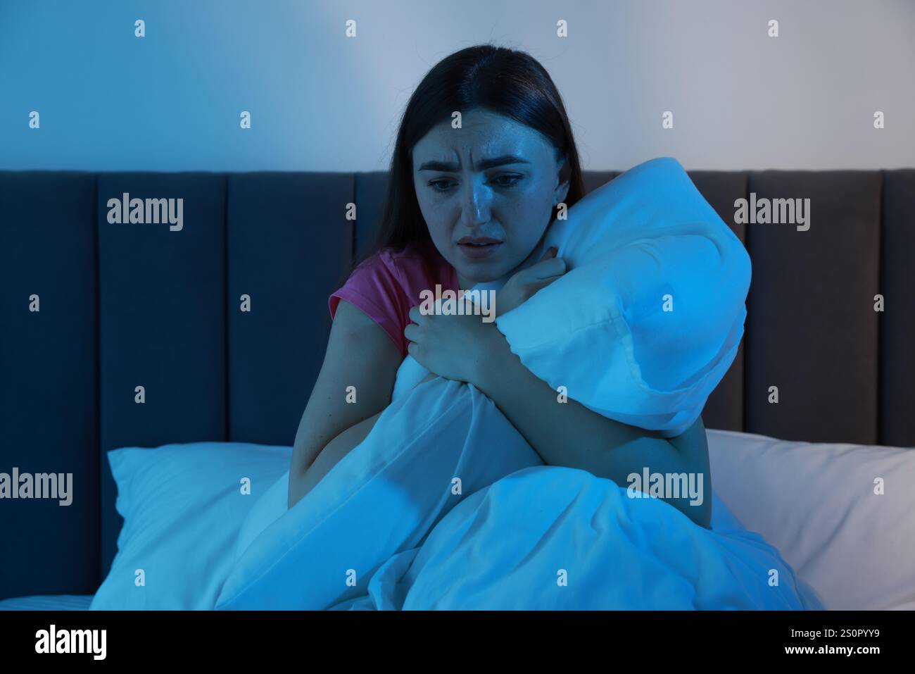 Fear of darkness. Scared young woman on bed in room at night Stock ...
