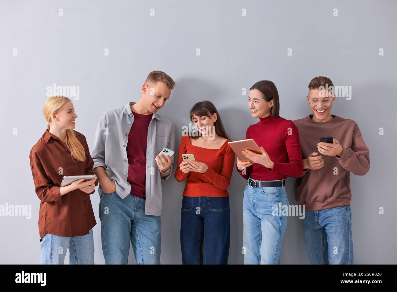 Group of people using different gadgets near light grey wall indoors ...