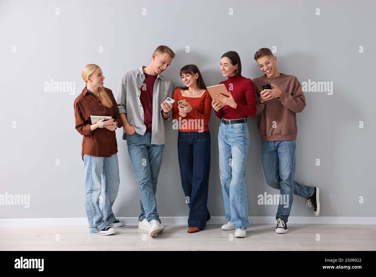 Group of people using different gadgets near light grey wall indoors ...