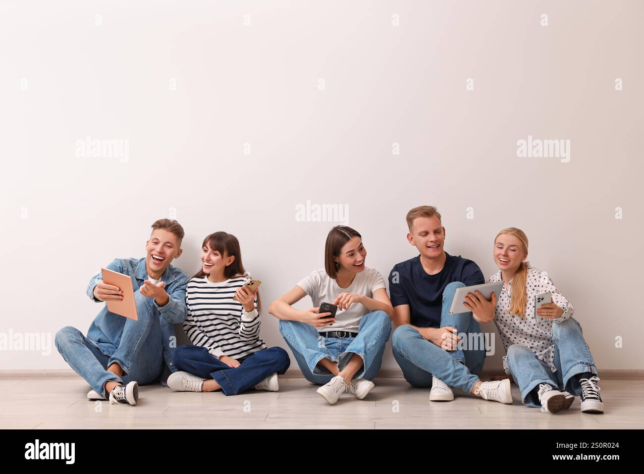 Group of people using different gadgets near white wall indoors. Modern ...