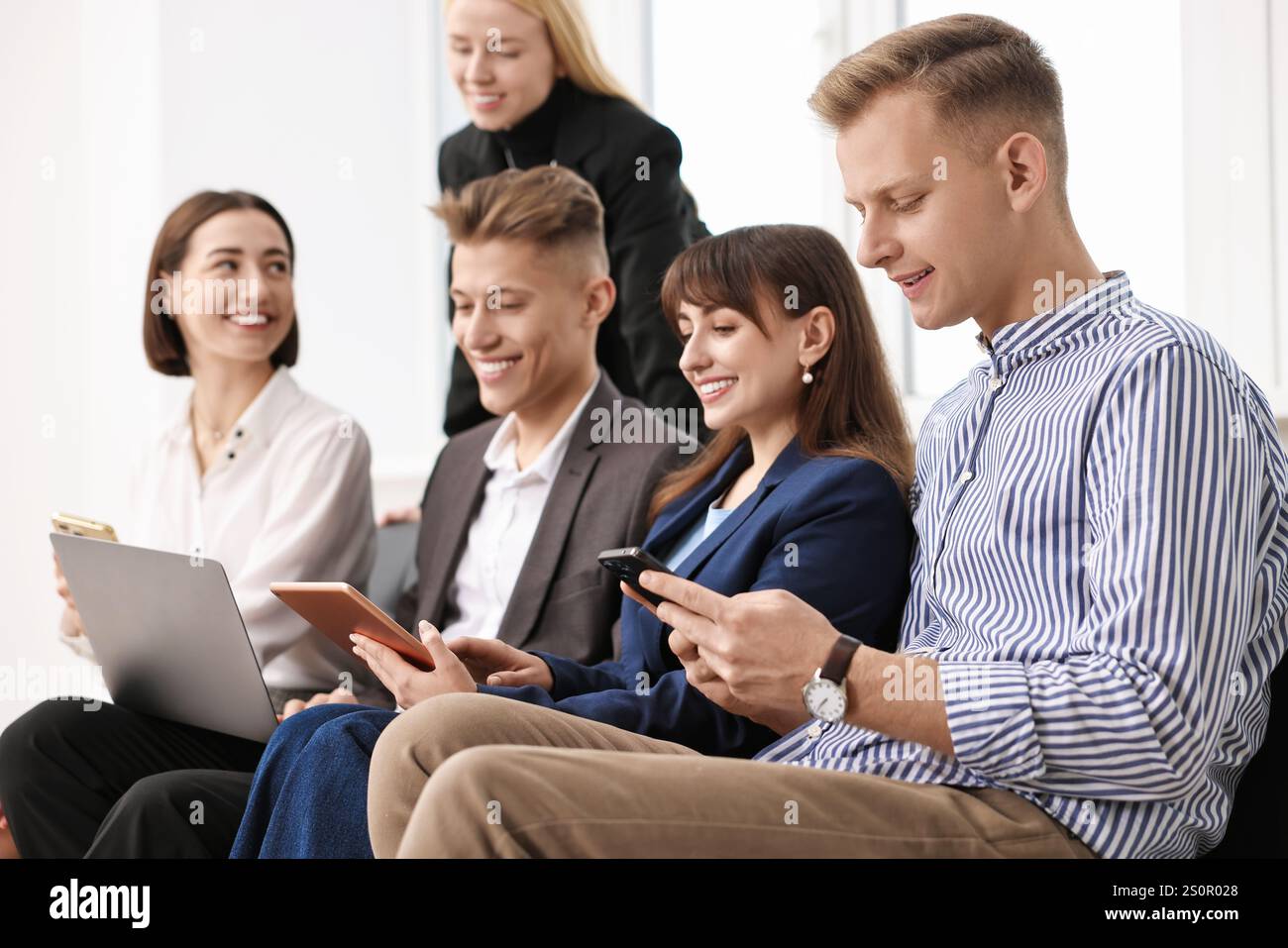 Group of people using different gadgets near window indoors. Modern ...