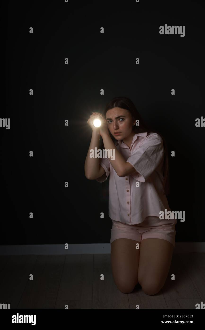 Fear of darkness. Scared young woman with flashlight indoors at night ...