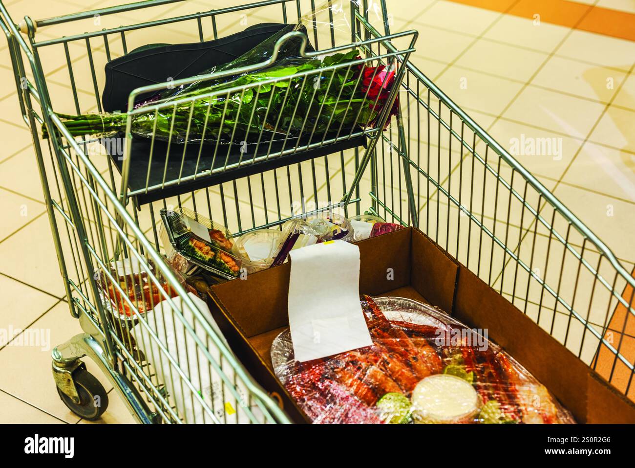 Shopping cart with red roses, packed food, and cardboard box on tiled ...